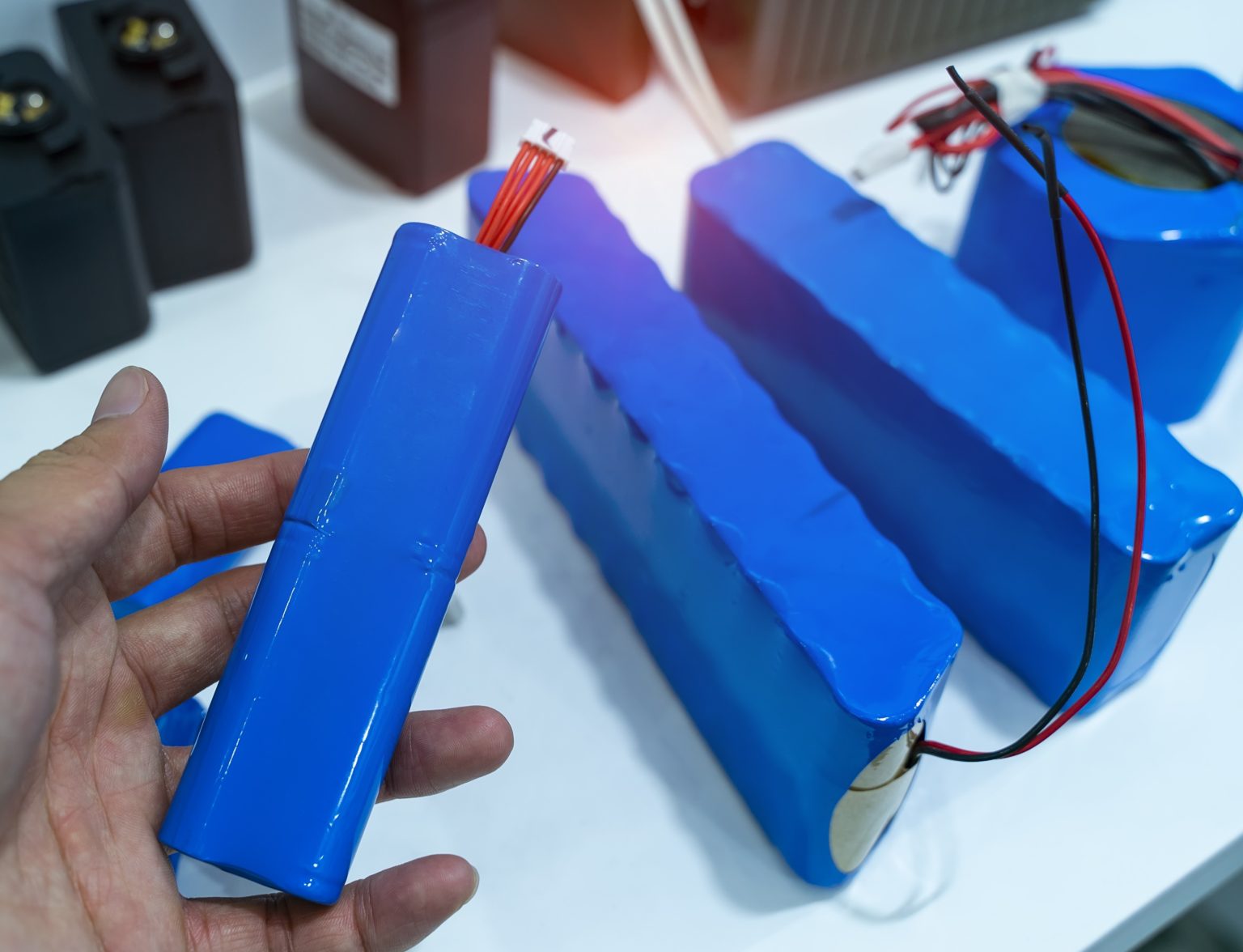 hand holding battery on white background - Excell Battery Co.